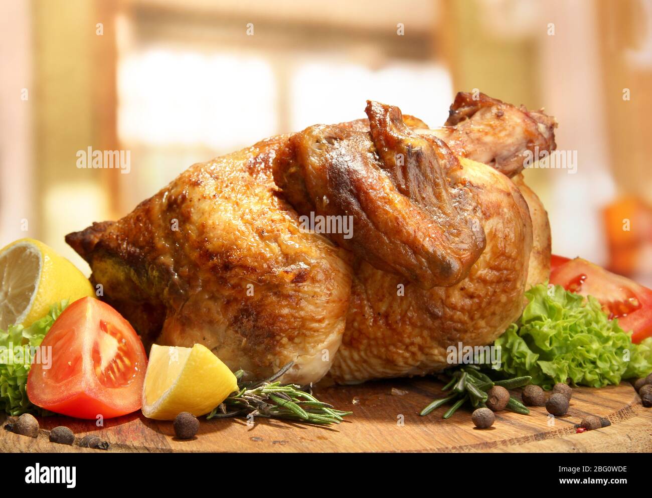 Whole roasted chicken with vegetables on plate, on wooden table in cafe ...