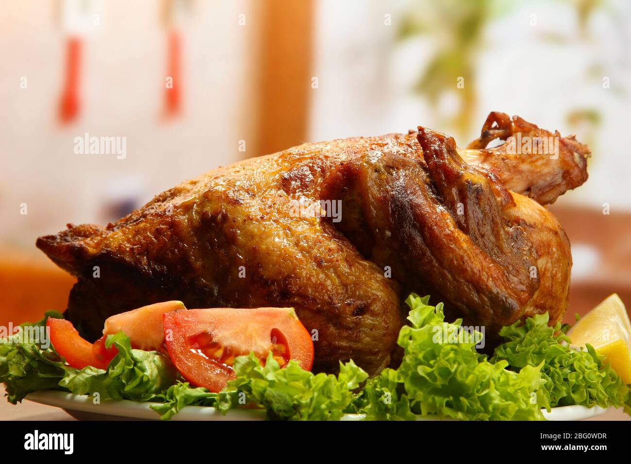 Whole roasted chicken with vegetables on plate, on wooden table in cafe ...