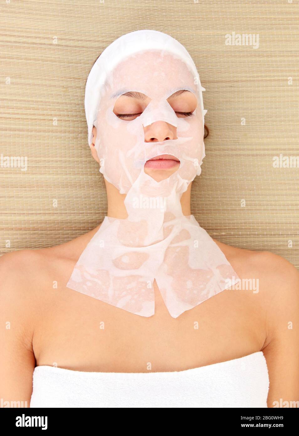 Young woman with cloth facial mask, on bamboo mat background Stock ...