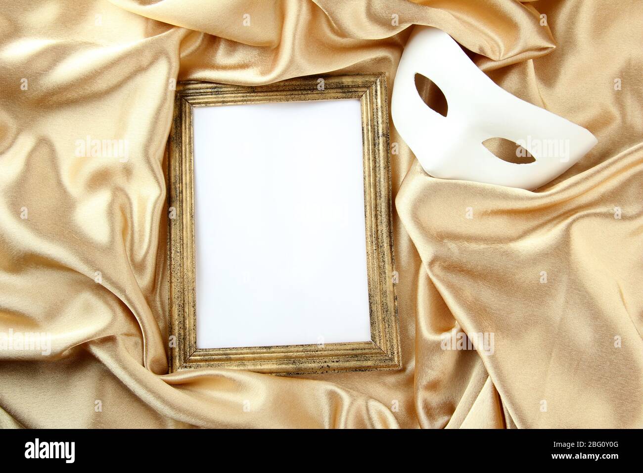 White mask and empty frame on golden silk fabric Stock Photo - Alamy