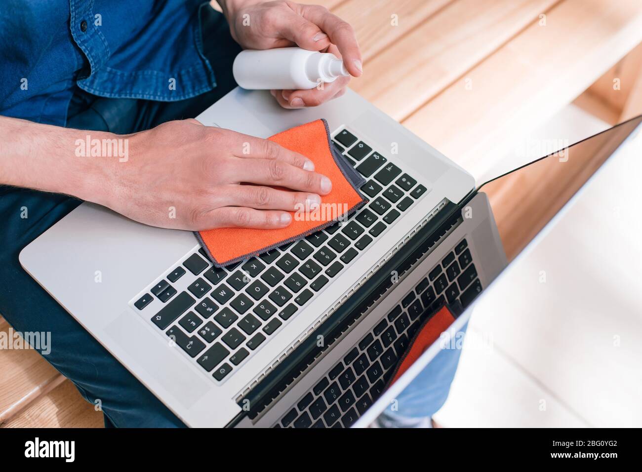 top view. a young man treating the laptop from bacteria coronavirus ...