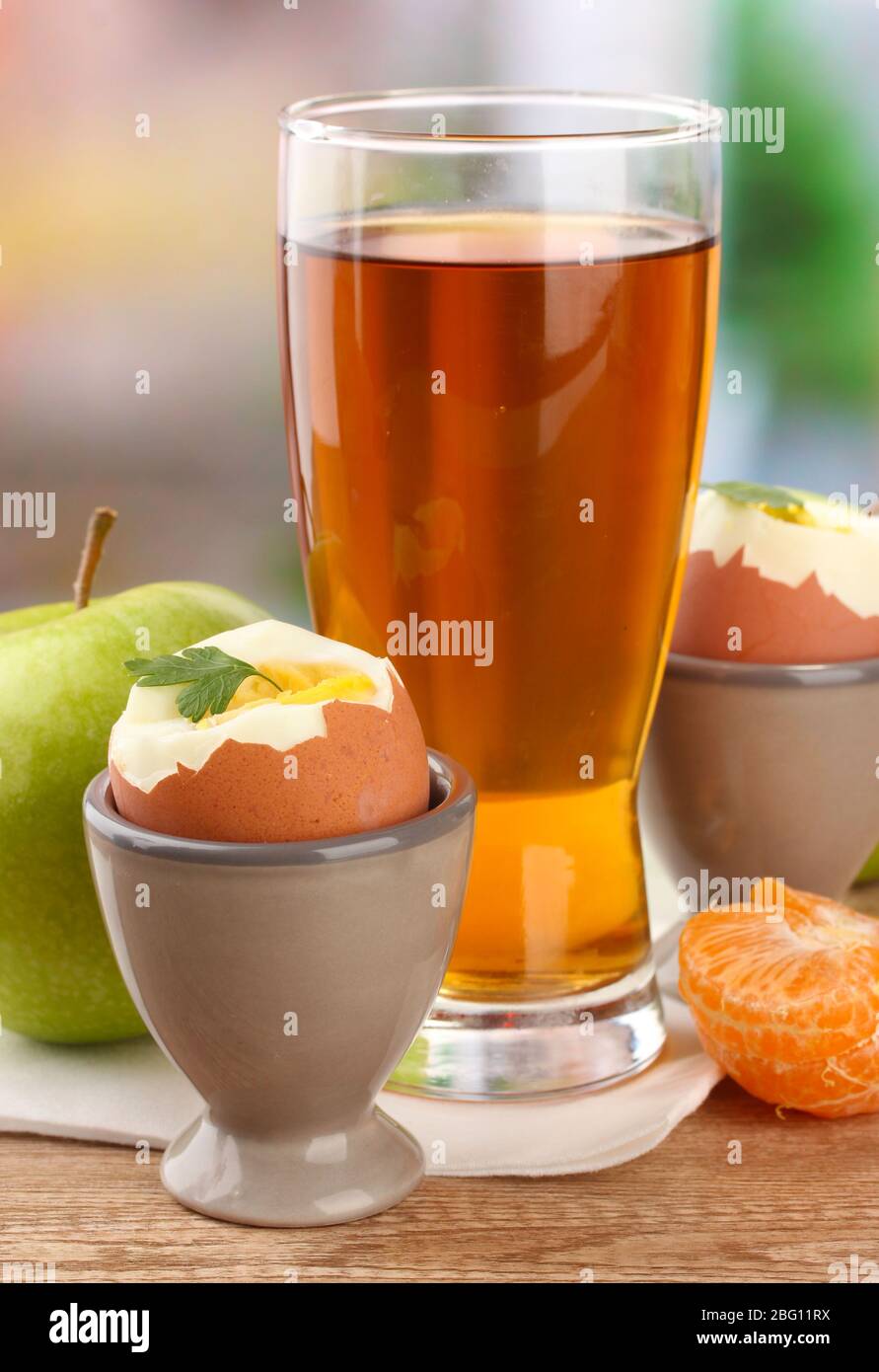 Light breakfast with boiled eggs and glass of juice on wooden table in ...