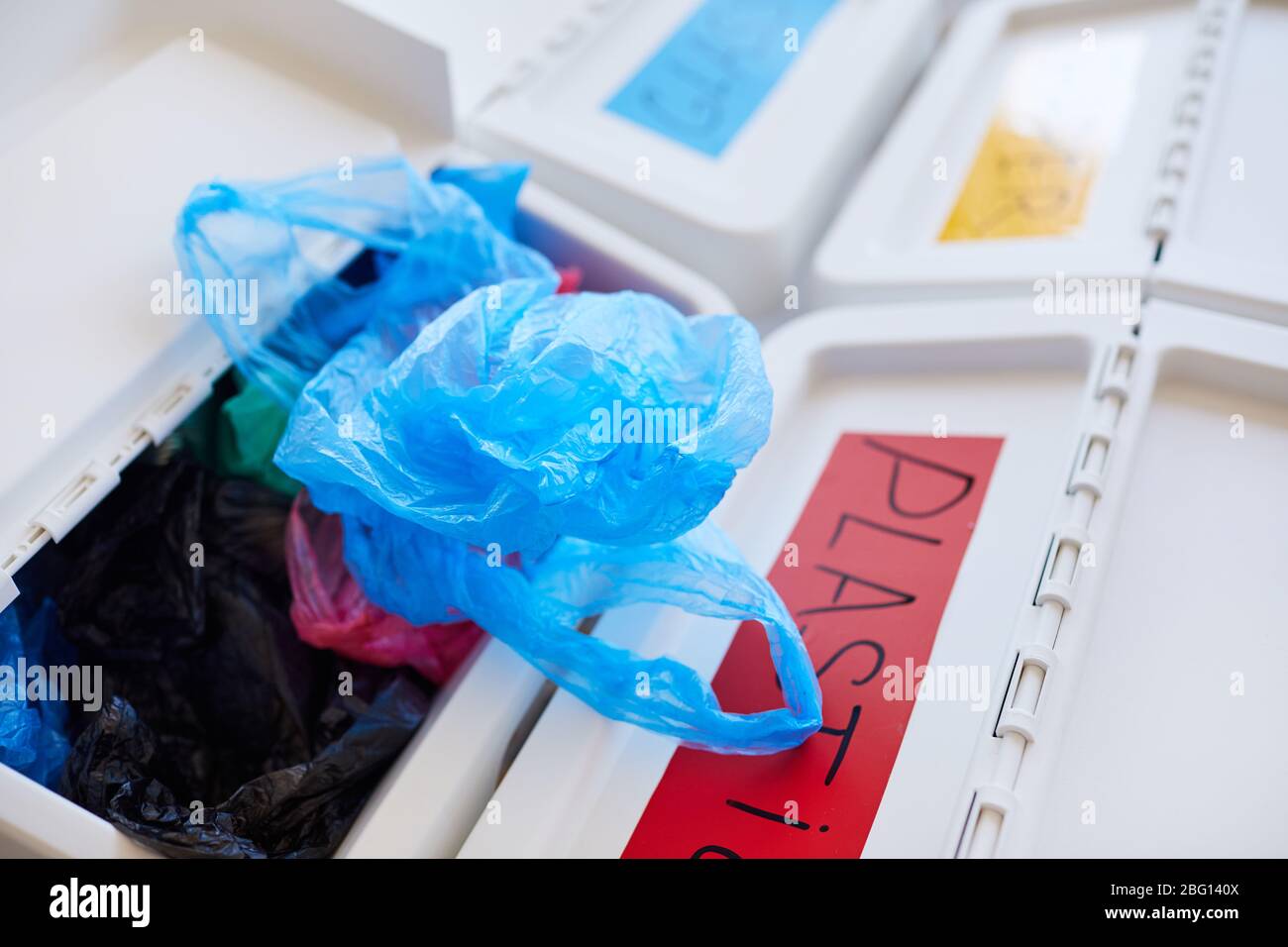 Close up of plastic bins labeled for storage and sorting waste at home ...