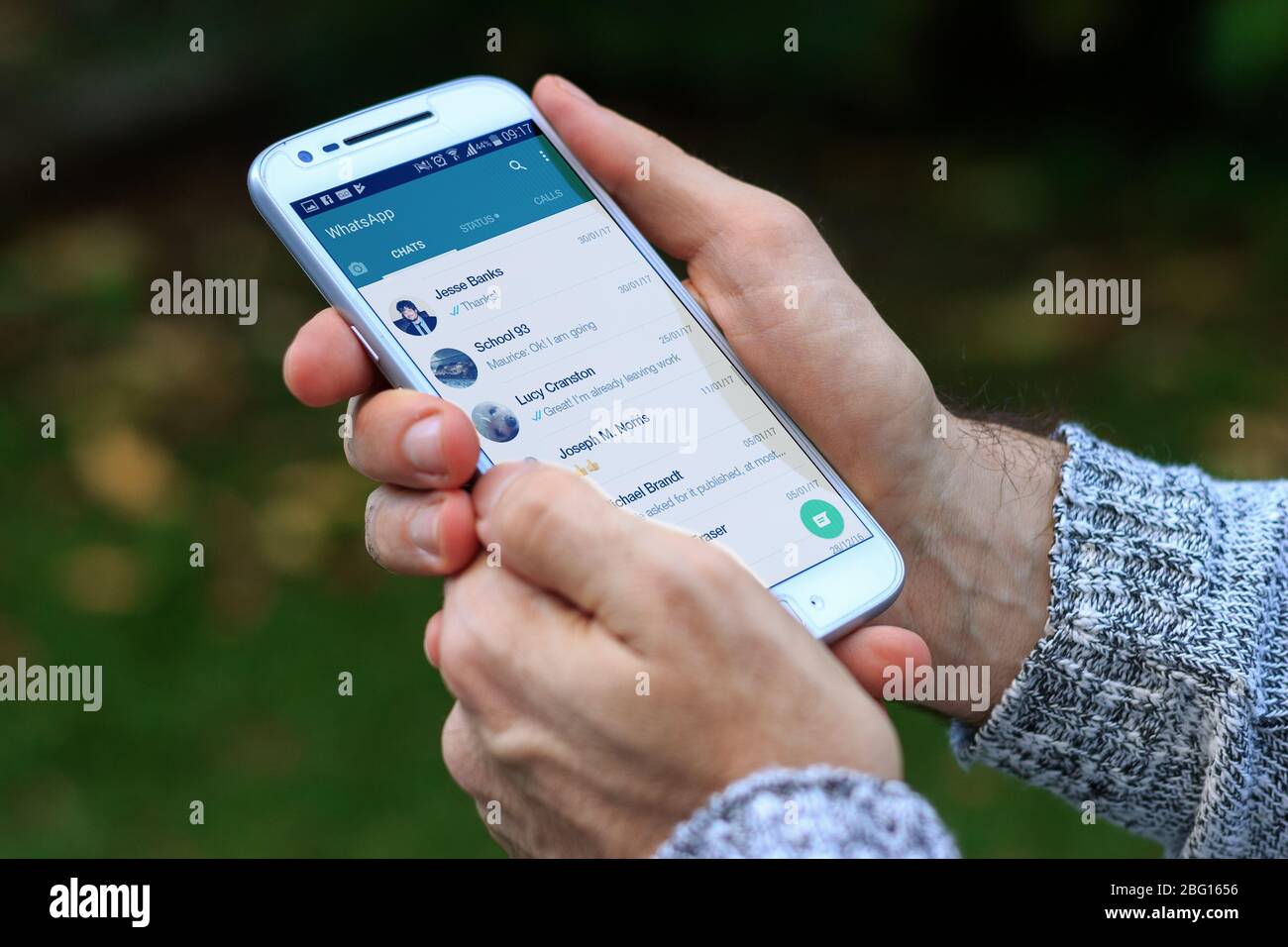 Man with a white cell phone in his hands. On the screen you can see the ...