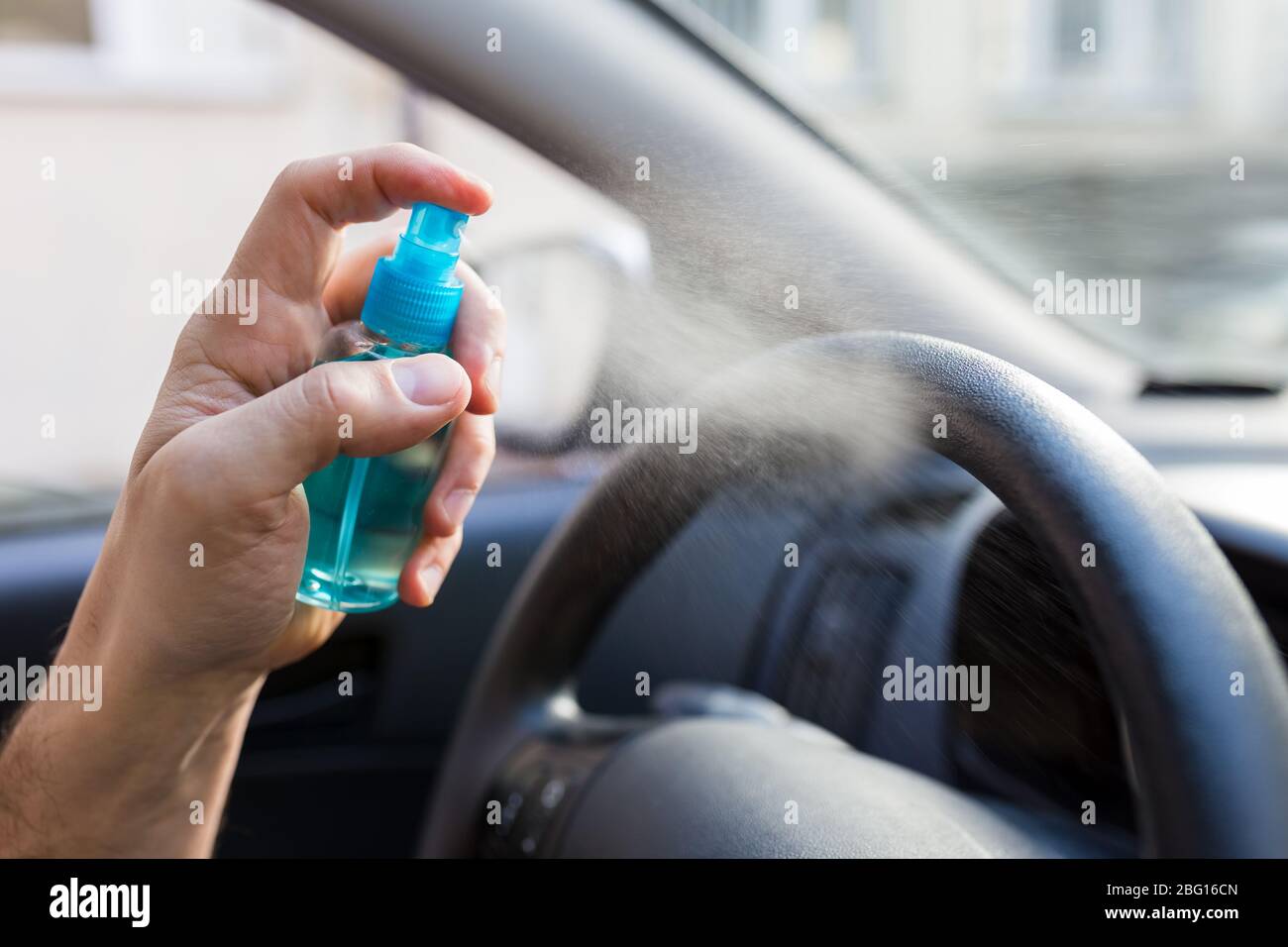 Man hand spraying alcohol disinfectant on car steering wheel to prevent ...