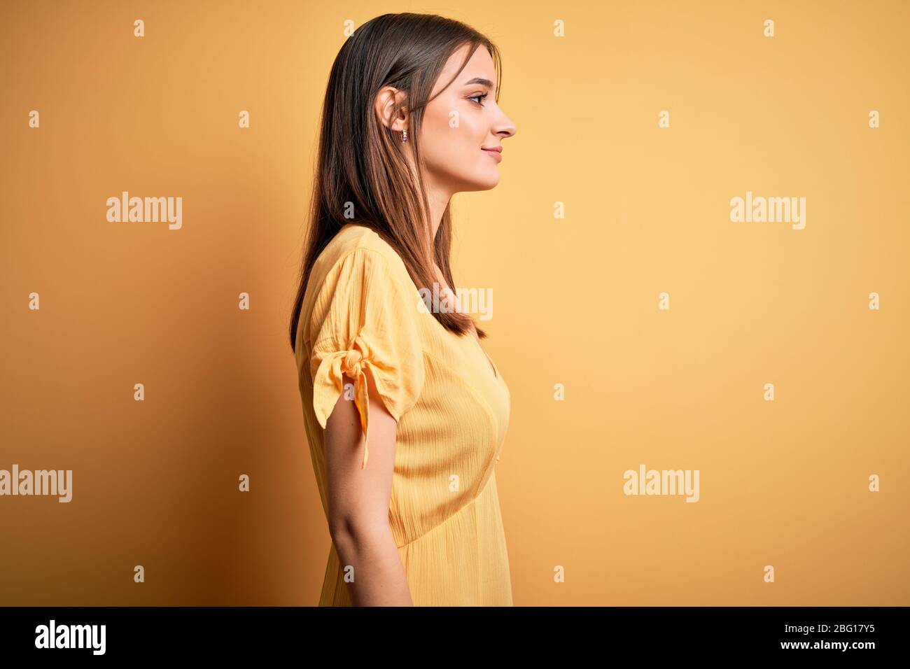 Young beautiful brunette woman wearing casual dress standing over ...