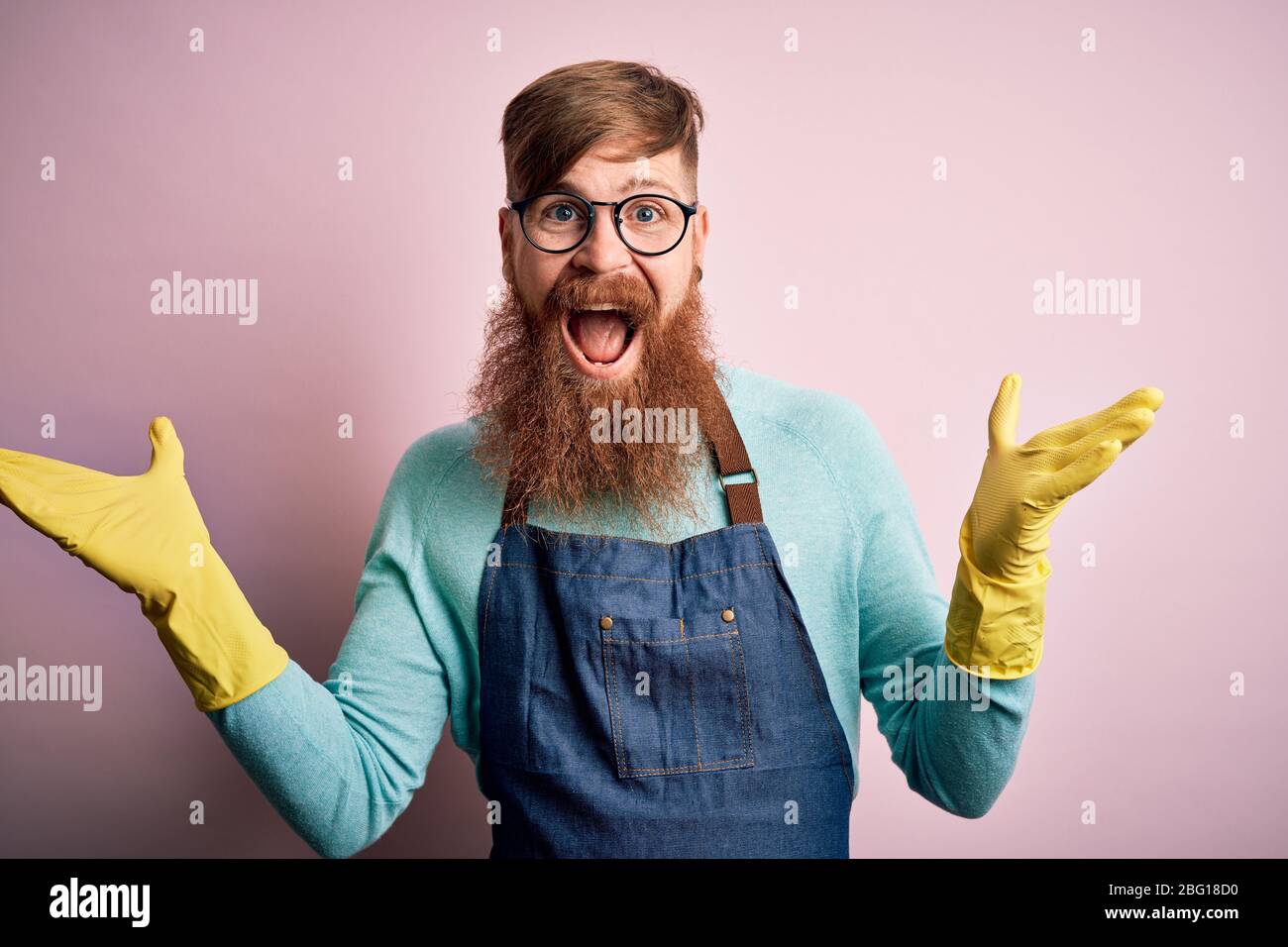 Irish redhead housekeeping man with beard wearing apron and washing ...