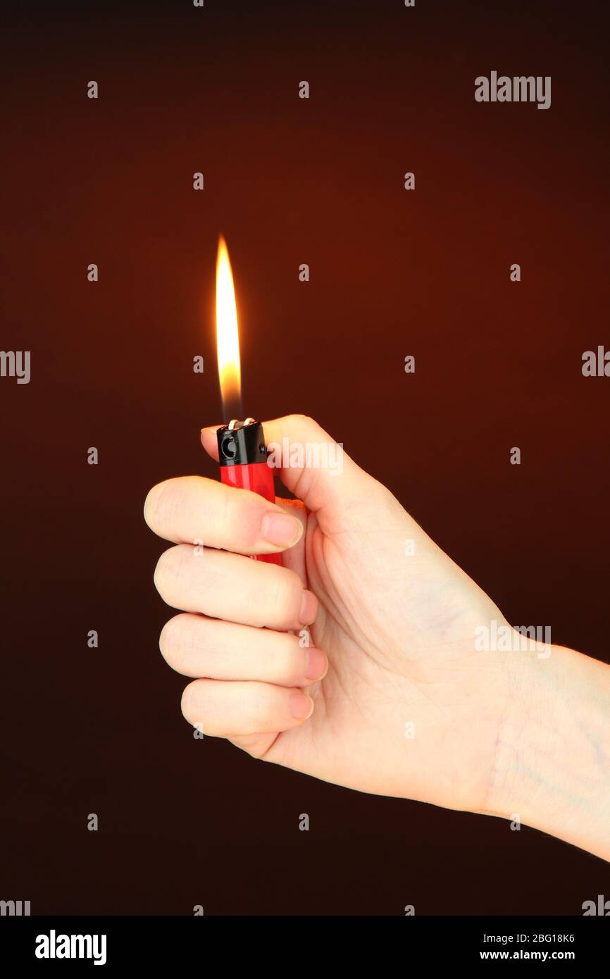Burning lighter in female hand, on dark brown background Stock Photo ...