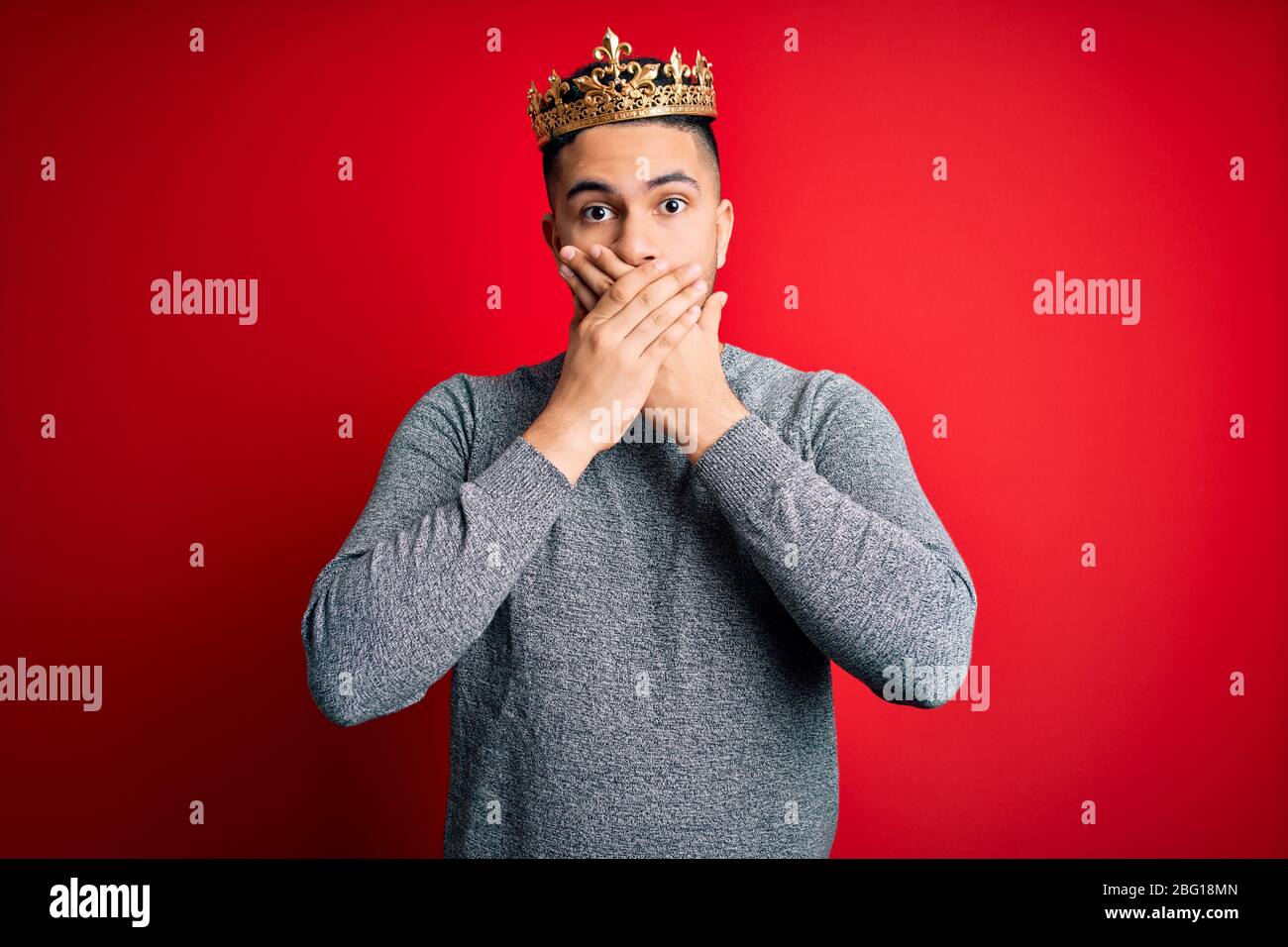 Young handsome man wearing golden crown of prince over isolated red ...