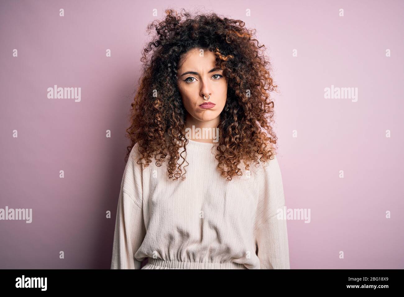 Beautiful woman with curly hair and piercing wearing casual sweater ...