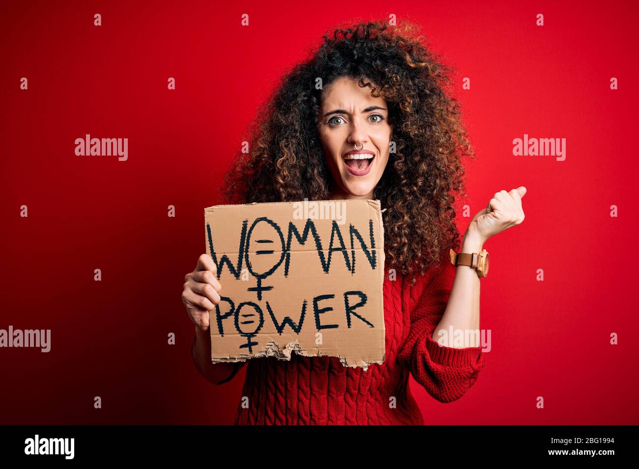 Activist with curly hair and piercing protesting holding poster with ...