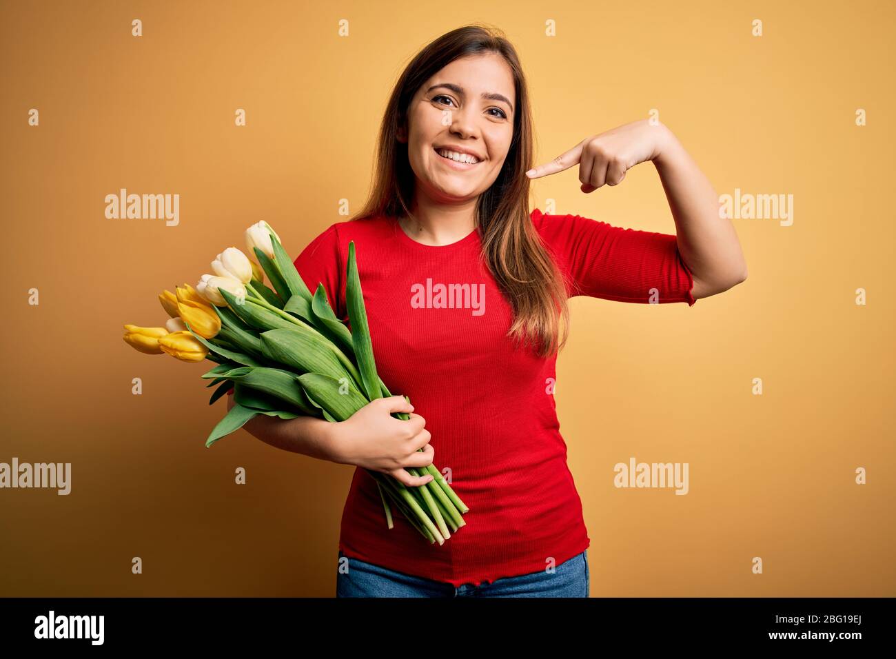 Young blonde woman holding romantic bouquet of tulips flowers over ...