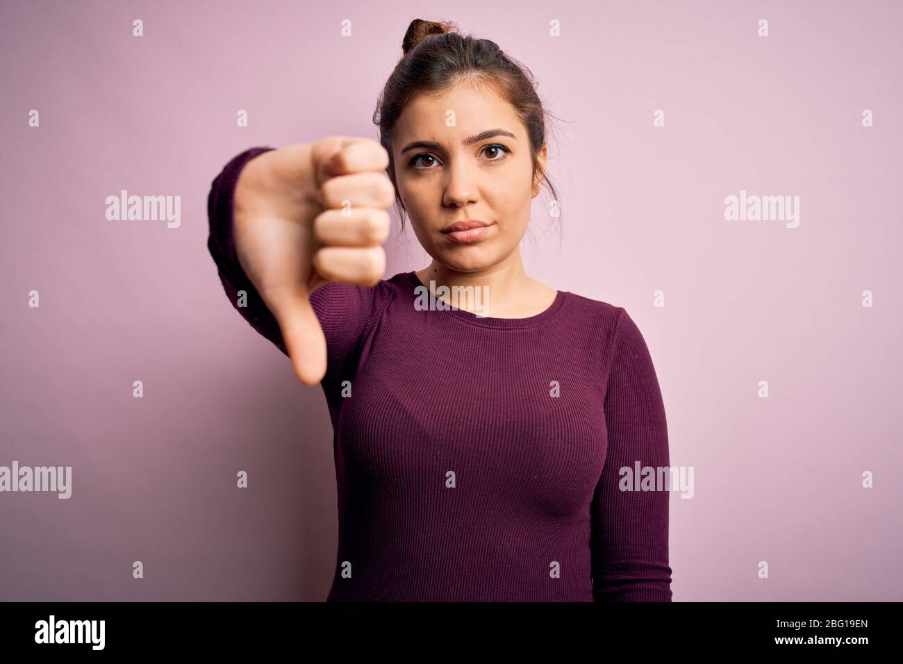 Beautiful young woman wearing casual bun hairstyle over pink isolated ...