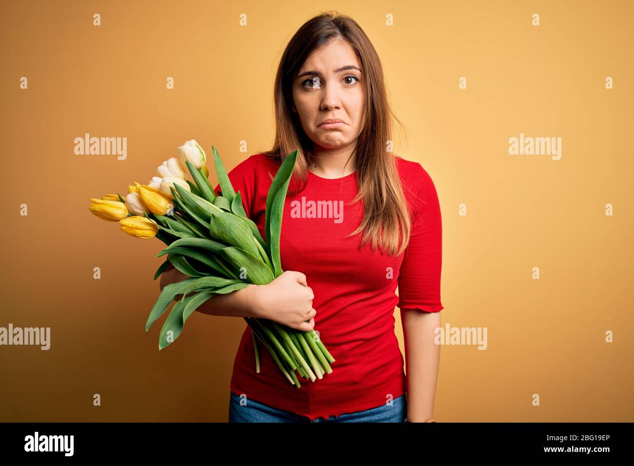 Young blonde woman holding romantic bouquet of tulips flowers over ...