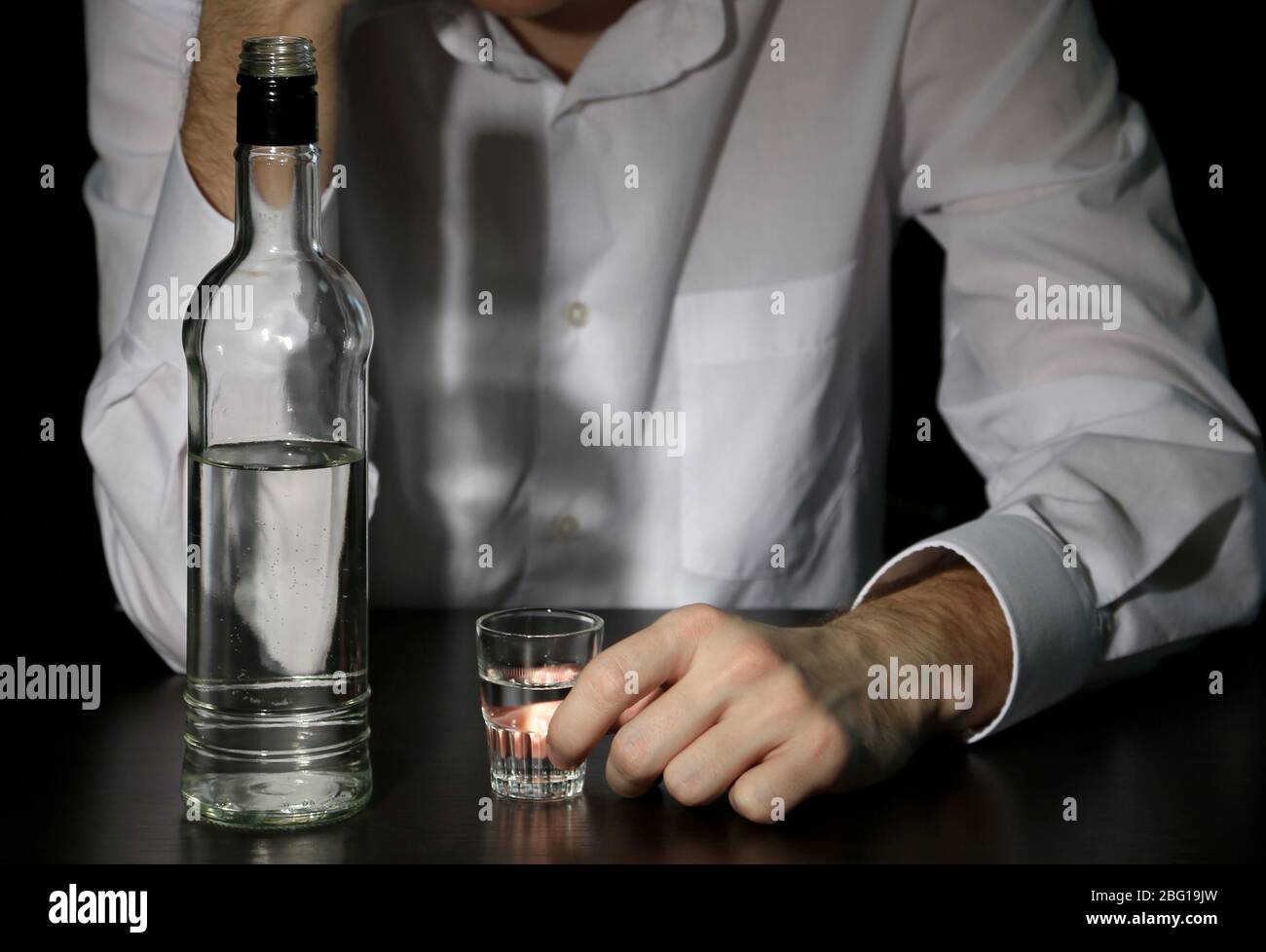 Man with bottle of alcohol, on black background Stock Photo - Alamy