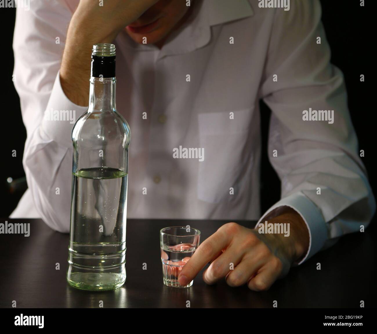 Man with bottle of alcohol, on black background Stock Photo - Alamy