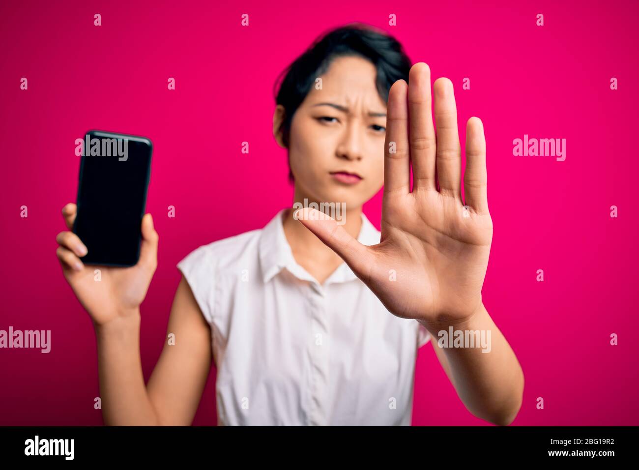 Young beautiful asian girl holding smartphone showing screen over ...