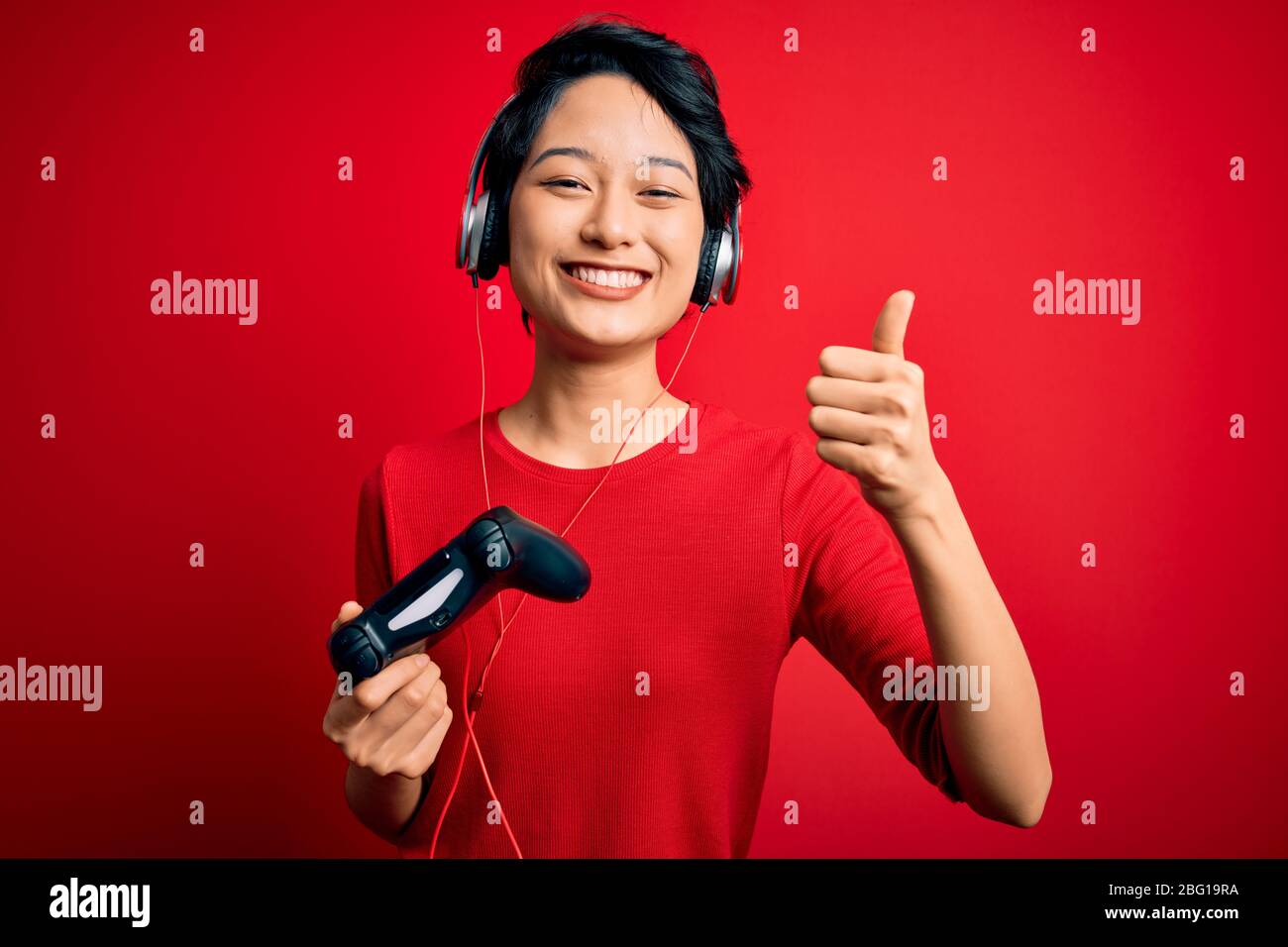 Young beautiful asian gamer girl playing video game using joystick and ...