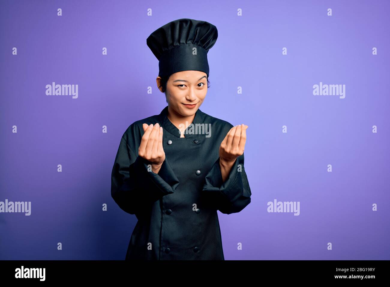 Young beautiful chinese chef woman wearing cooker uniform and hat over ...