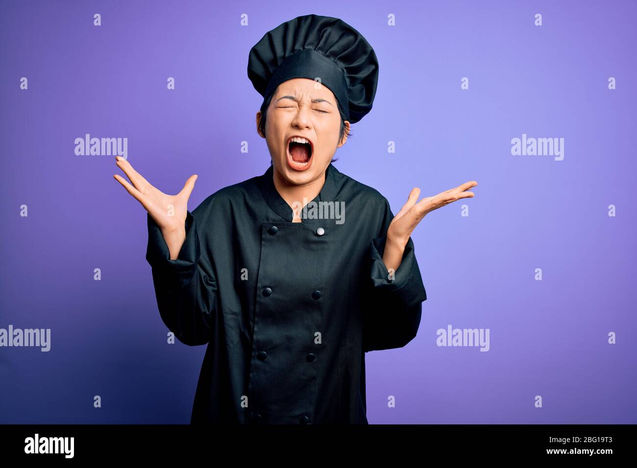Young beautiful chinese chef woman wearing cooker uniform and hat over ...
