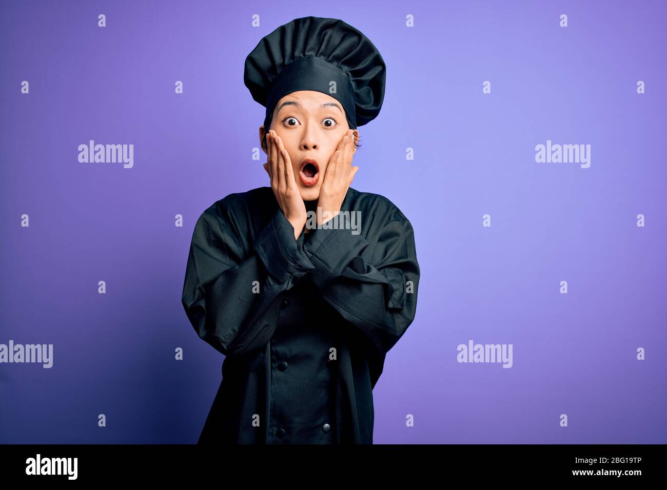 Young beautiful chinese chef woman wearing cooker uniform and hat over ...