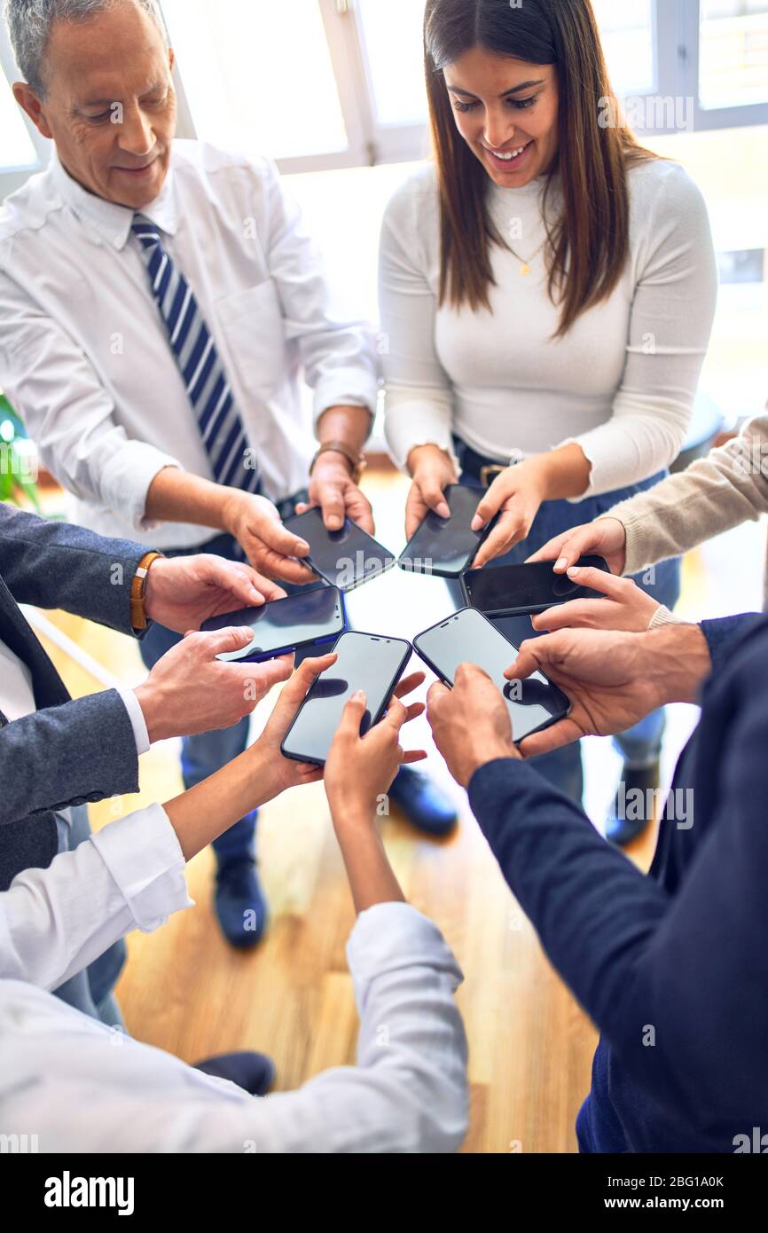 Group of business workers standing with hands together using smartphone ...