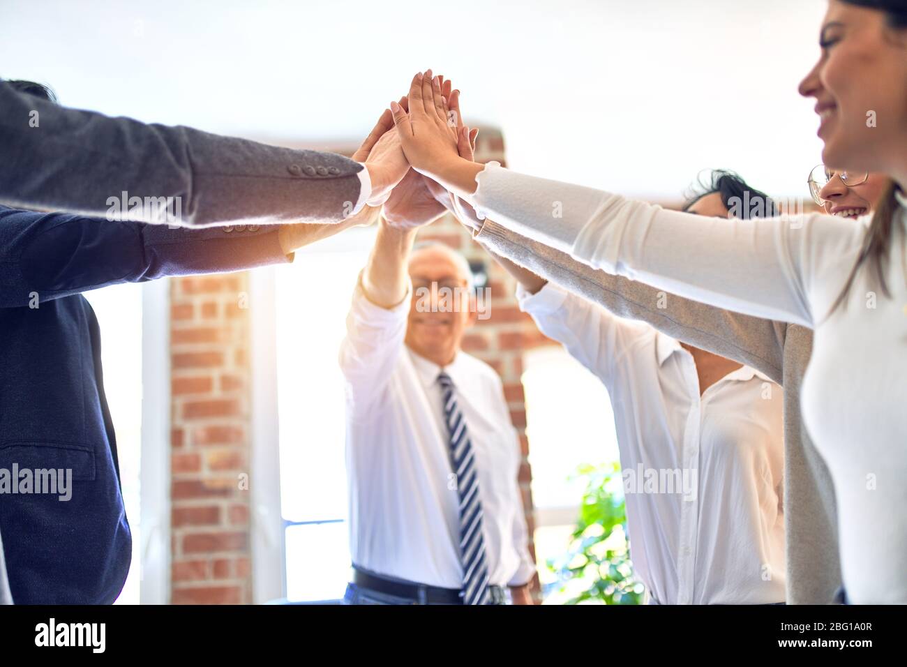 Group of business workers standing with hands together at the office ...