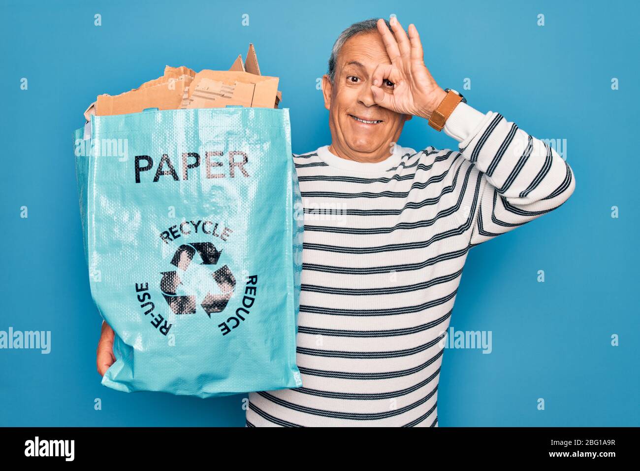 Senior grey-haired man recycling holding bag with cardboard to recycle ...