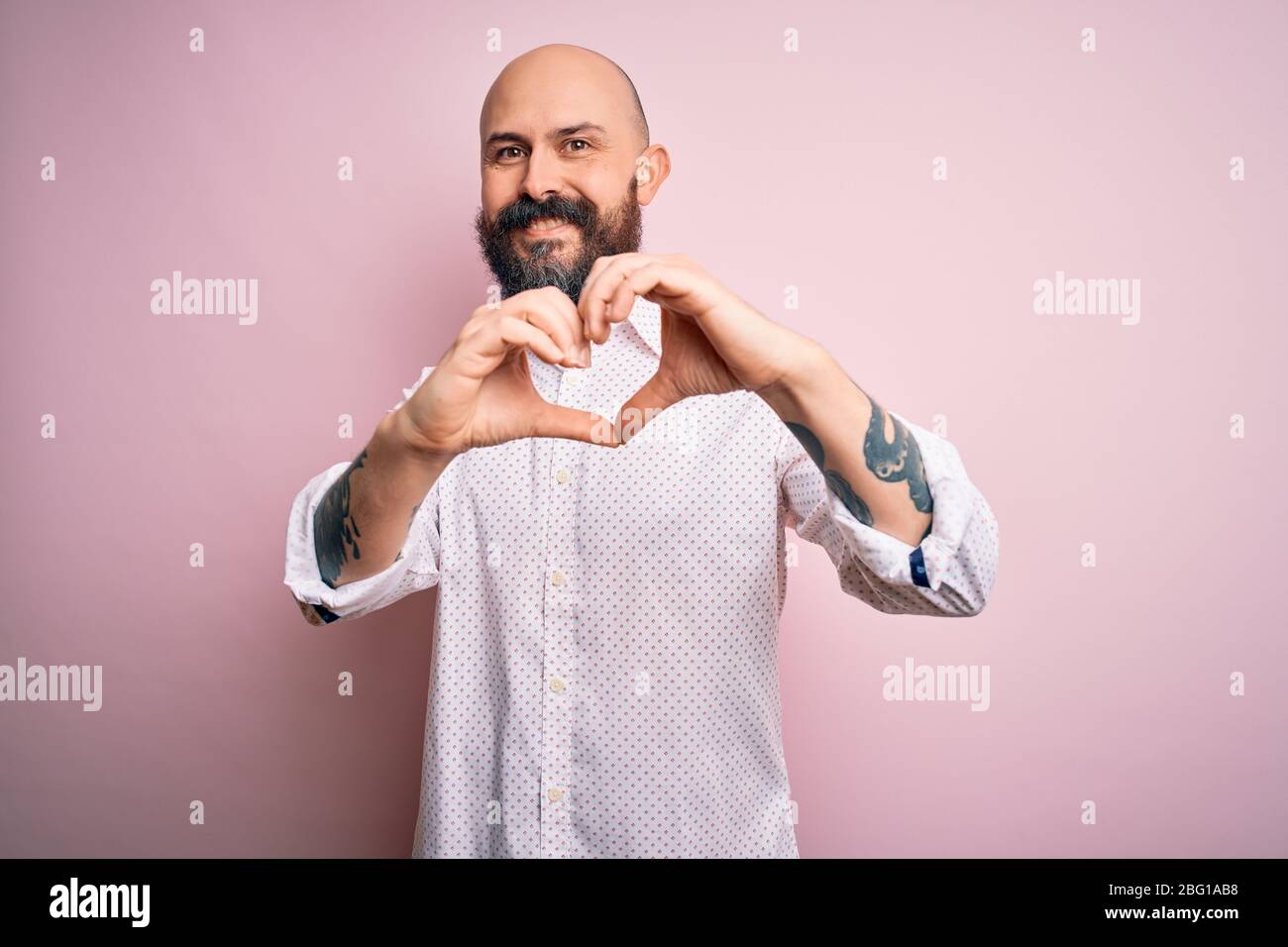 Handsome bald man with beard wearing elegant shirt over isolated pink ...