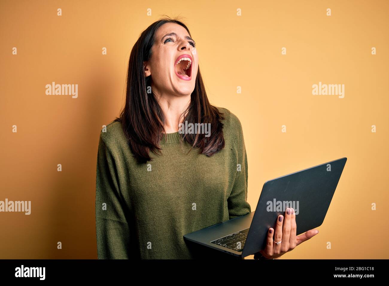 Young brunette woman with blue eyes working using computer laptop over ...
