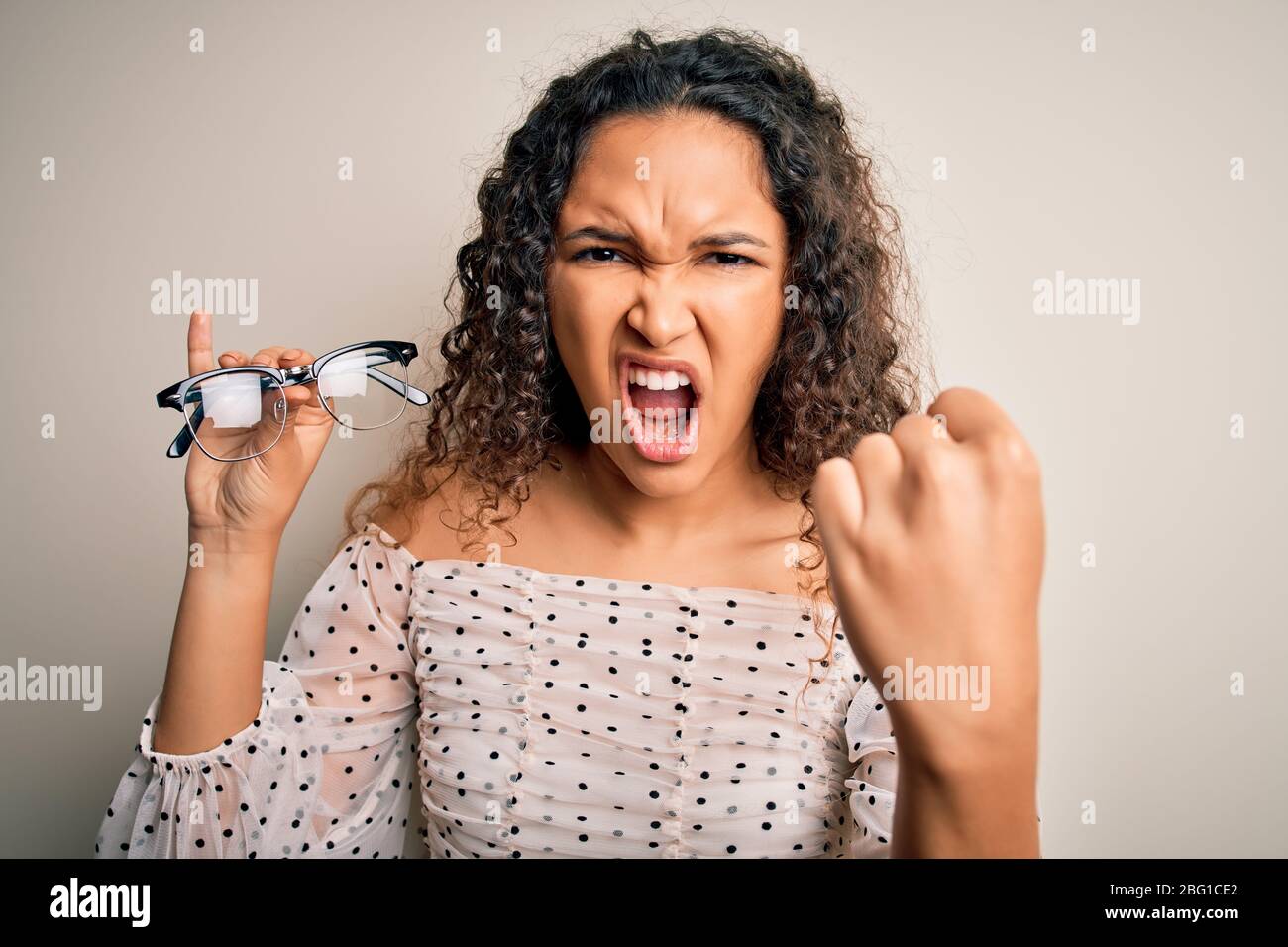 Young beautiful optical woman with curly hair holding vision glasses ...