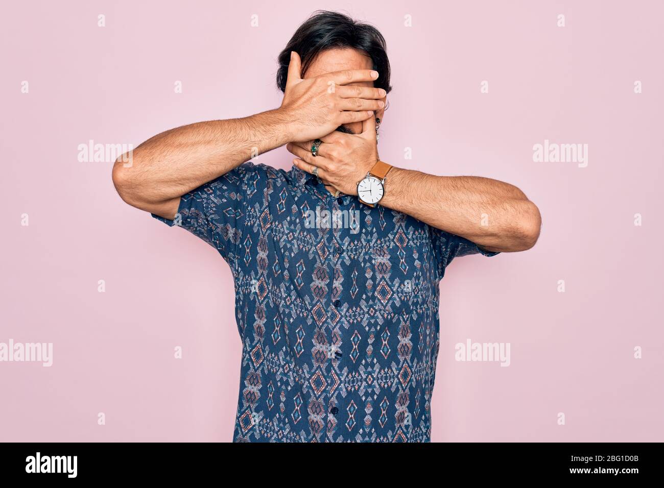 Young handsome hispanic bohemian man wearing hippie style over pink ...