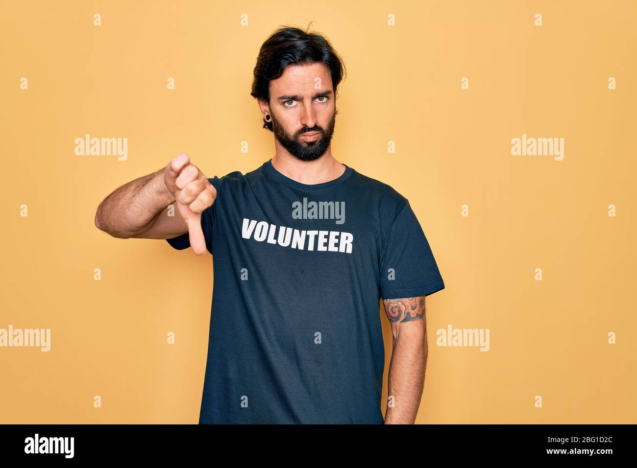 Young handsome hispanic volunteer man wearing volunteering t-shirt as ...