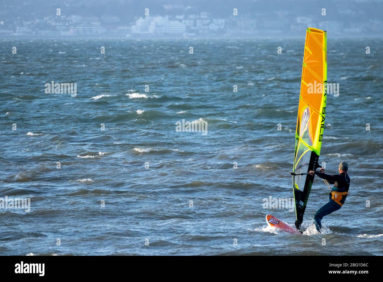 A lone windsurfer riding his board over waves Stock Photo - Alamy