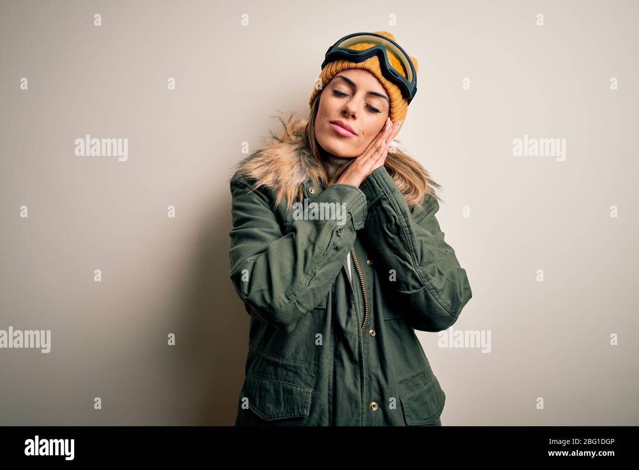 Young brunette skier woman wearing snow clothes and ski goggles over ...