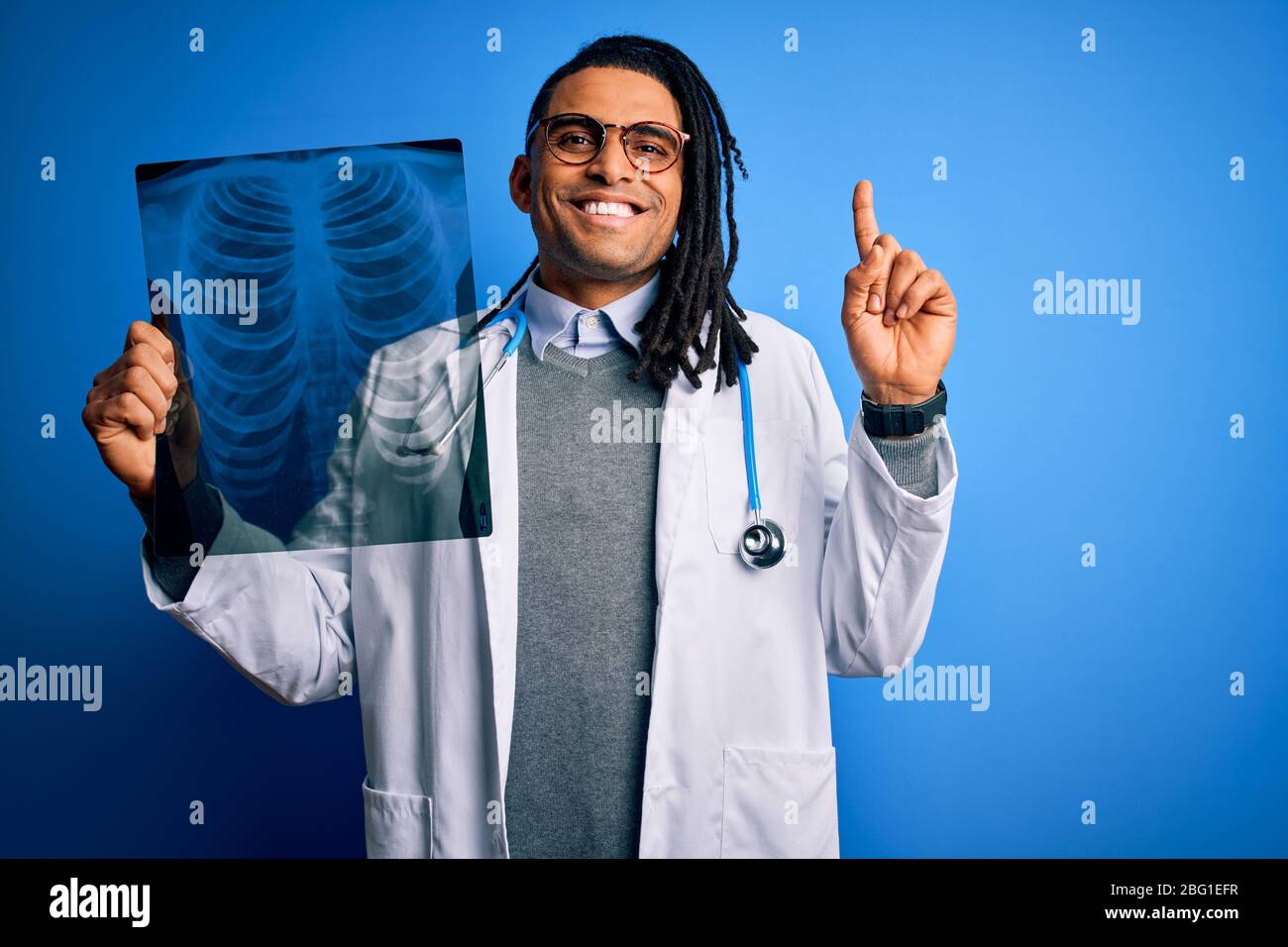 Young african american afro doctor man with dreadlocks holding chest ...
