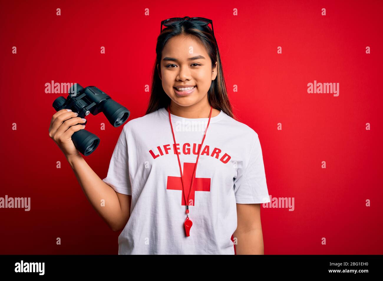 Young asian lifeguard girl wearing t-shirt with red cross using whistle ...