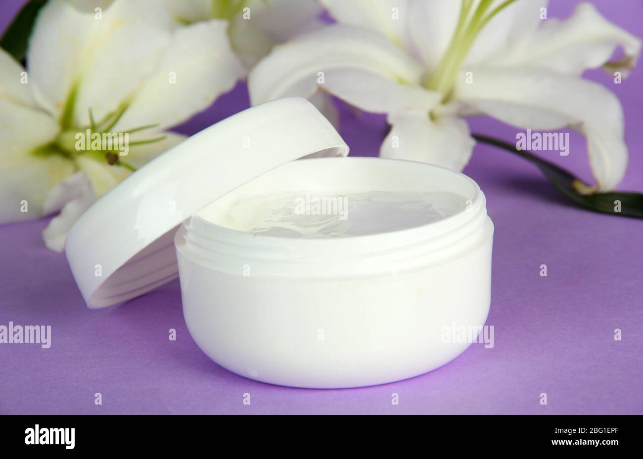 Cosmetic cream and beautiful lily, on purple background Stock Photo - Alamy