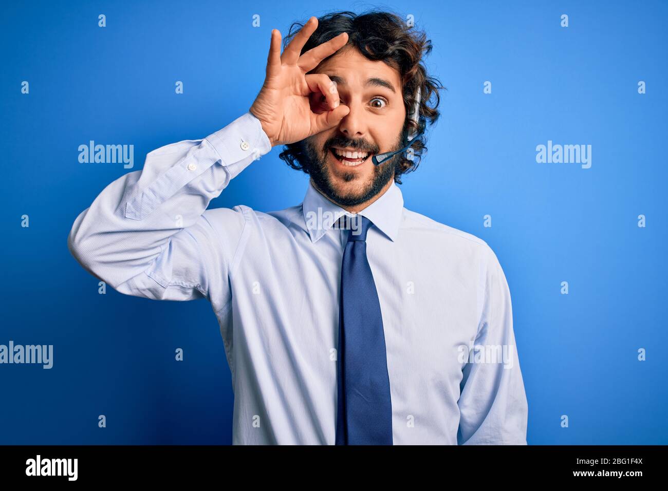 Young handsome call center agent man with beard working using headset ...