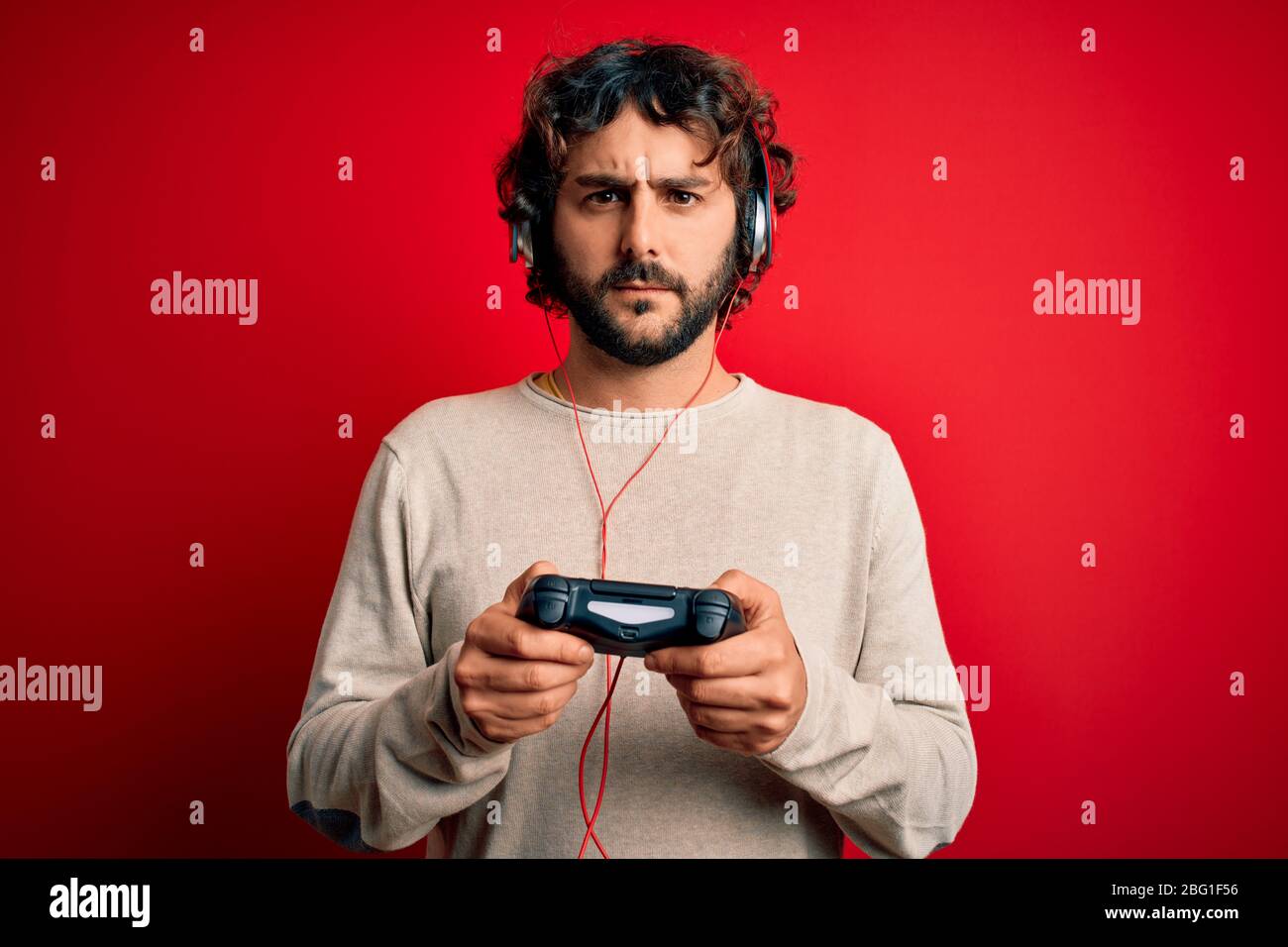 Young gamer man with curly hair and beard playing video game using ...