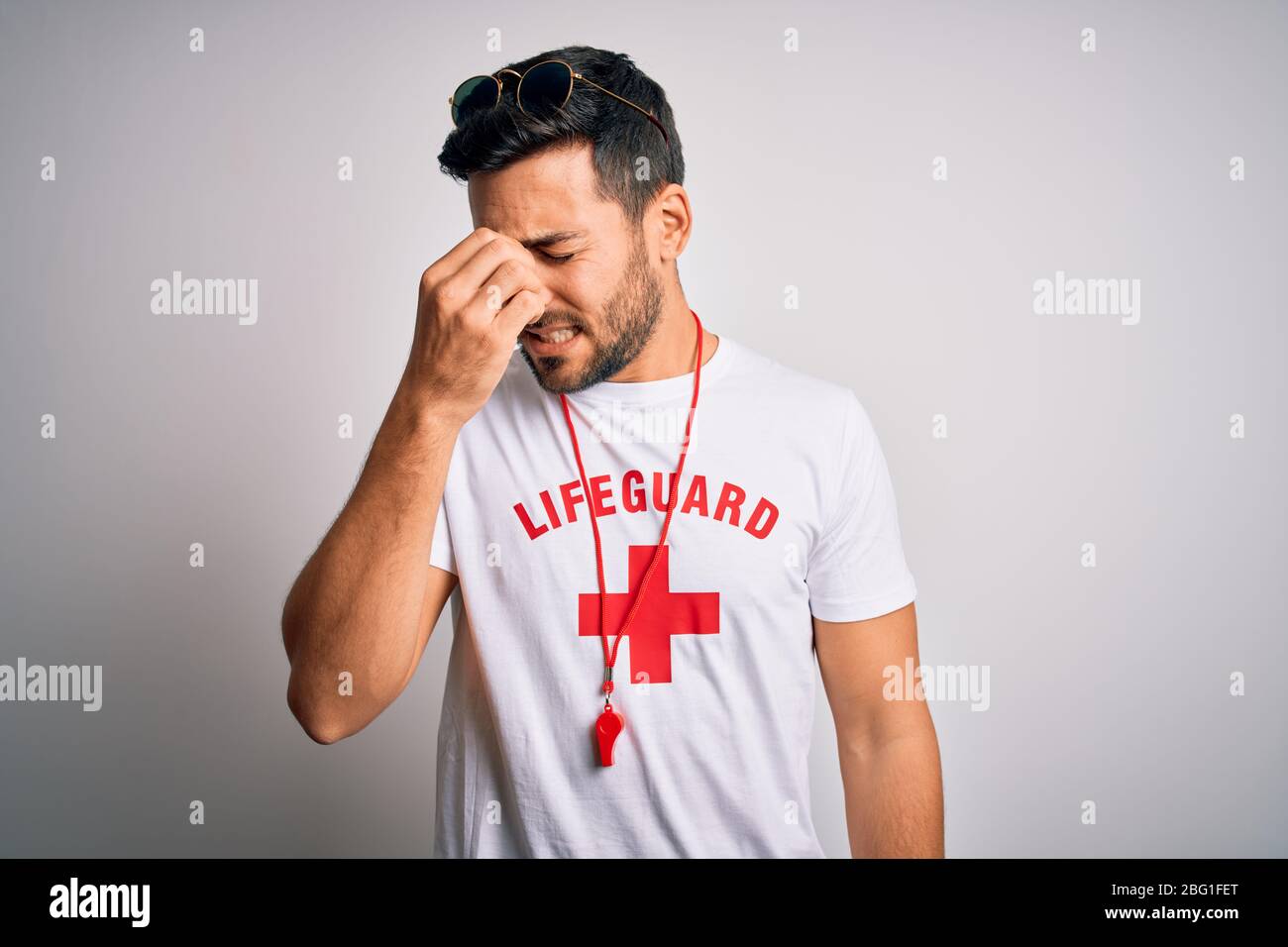 Young handsome lifeguard man with beard wearing t-shirt with red cross ...