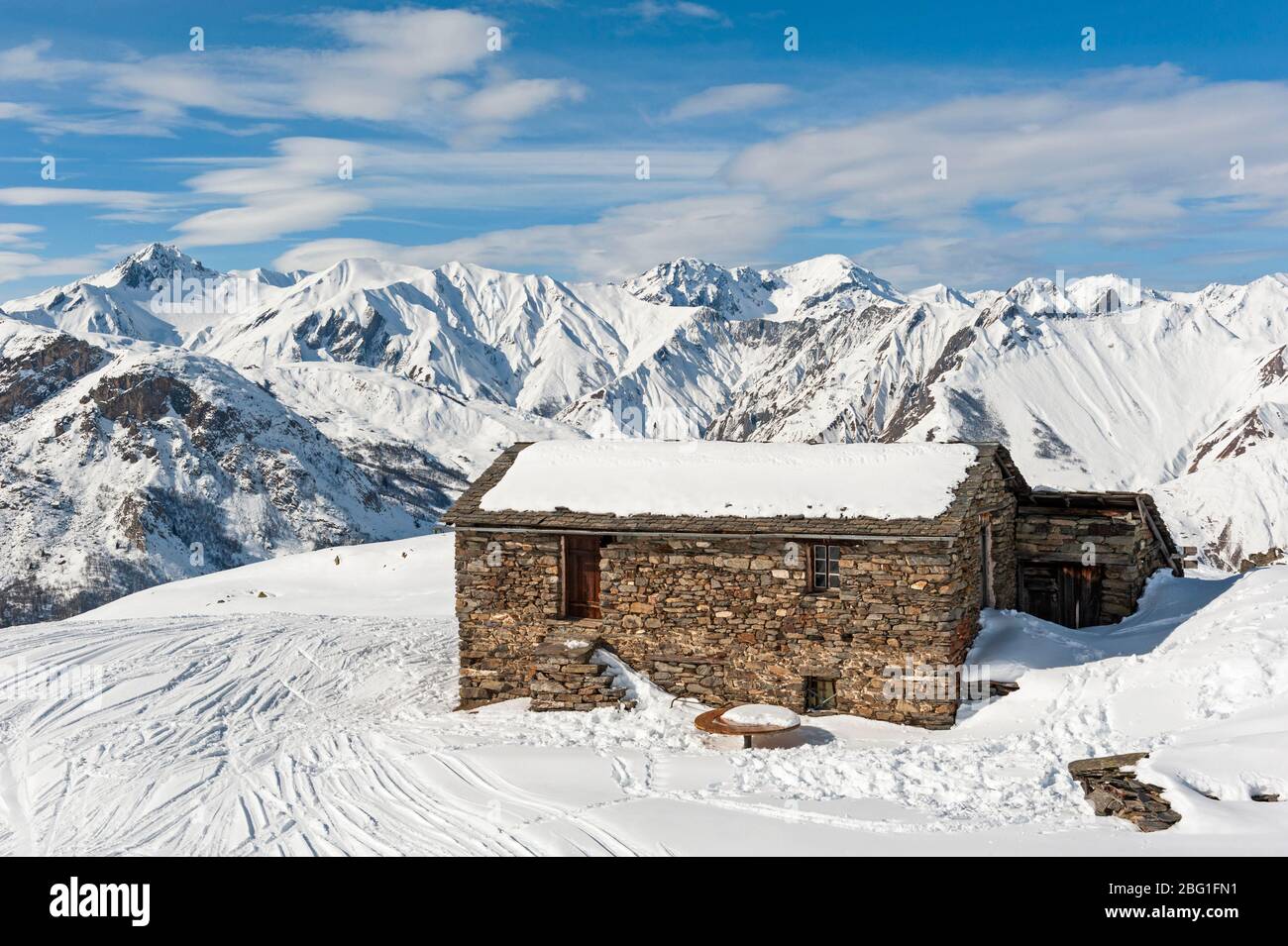 Remote stone house hut on an alpine mountain slope in winter covered ...