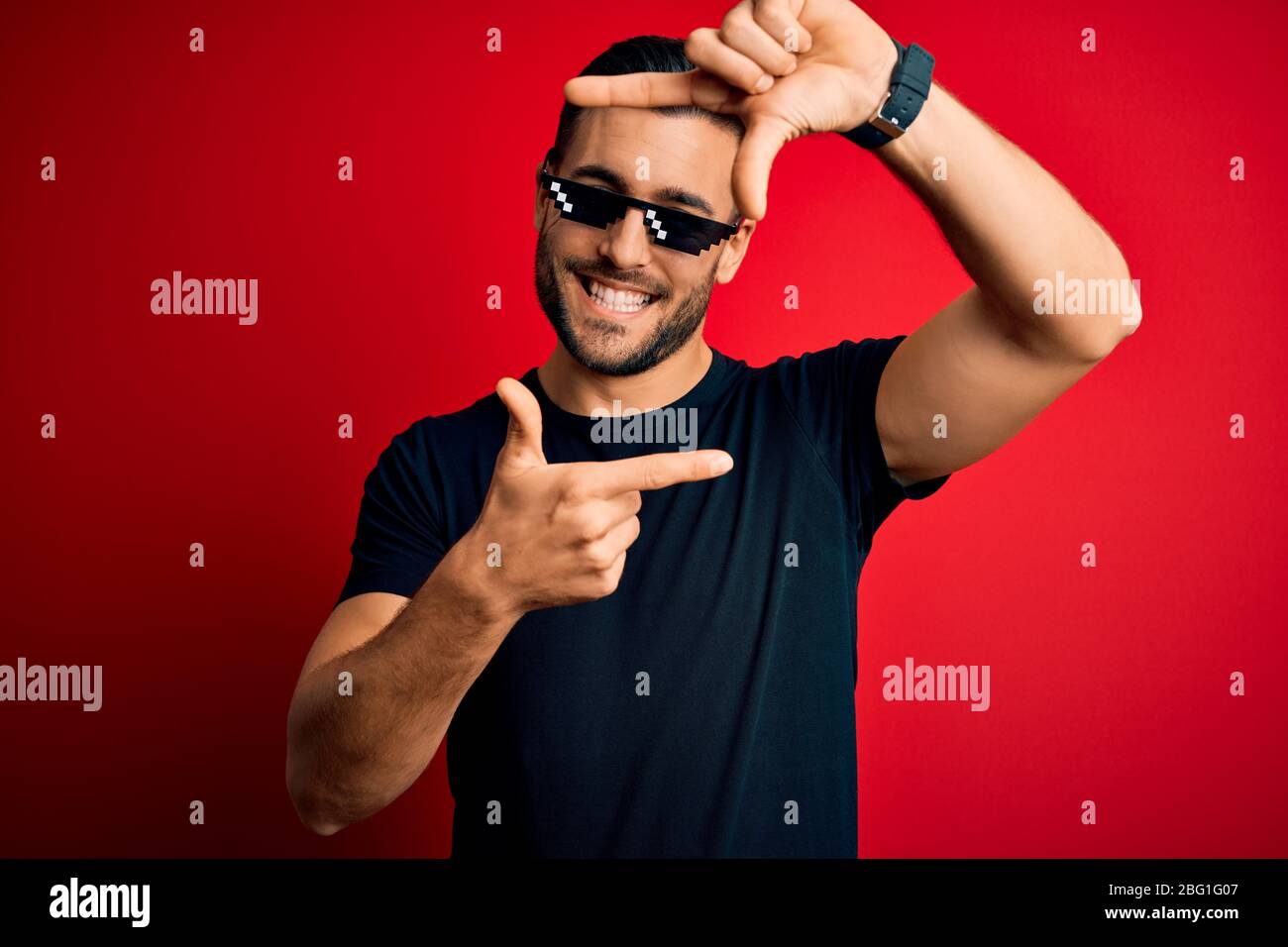 Young handsome man wearing funny thug life sunglasses over isolated red ...