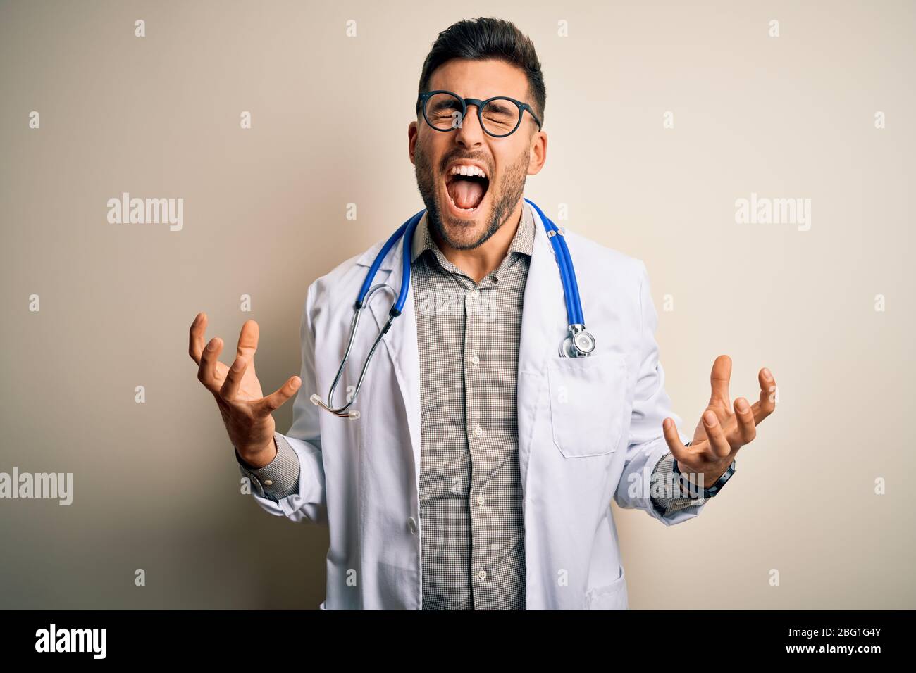 Young doctor man wearing glasses, medical white robe and stethoscope ...