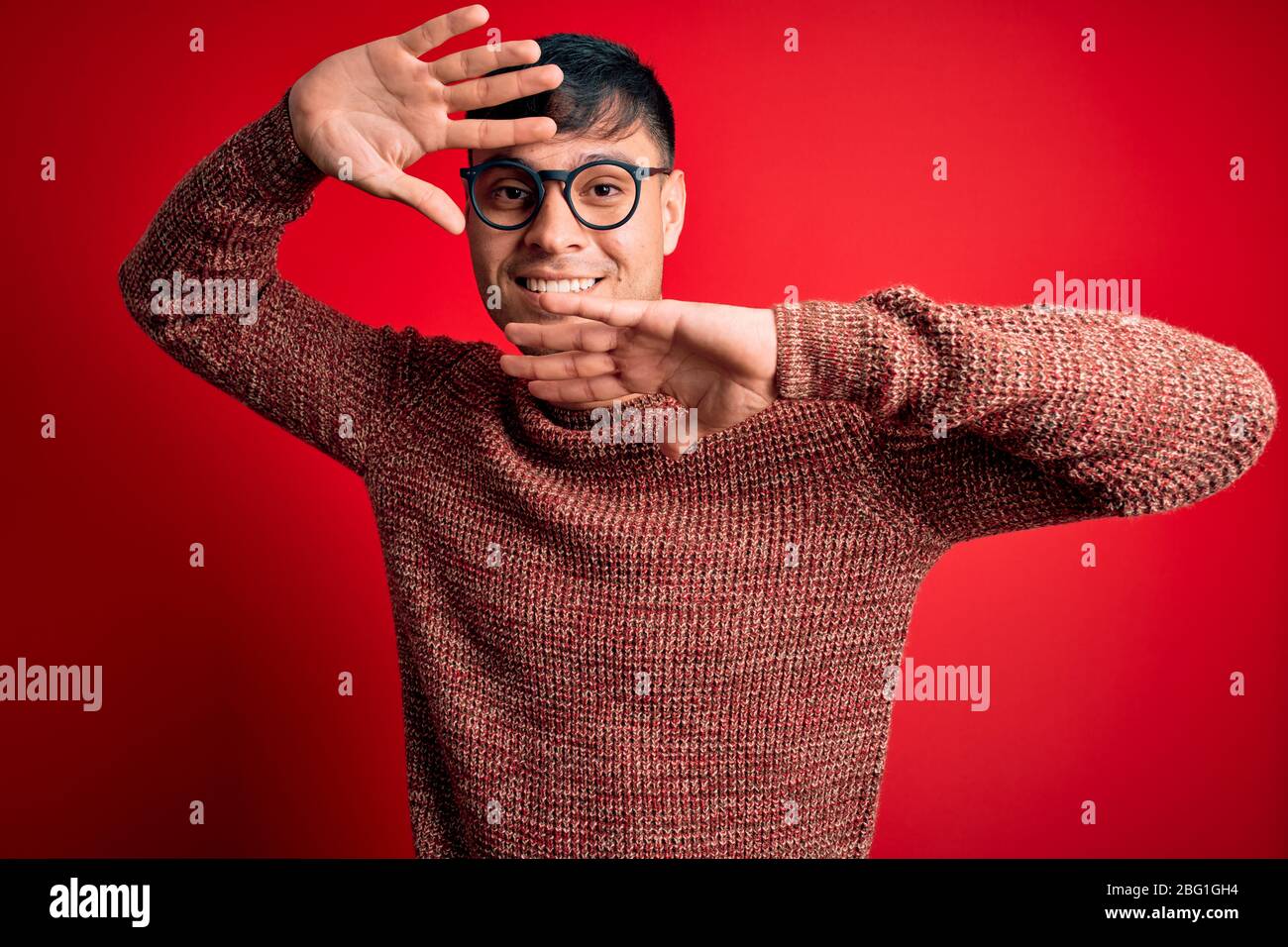 Young handsome hispanic man wearing nerd glasses over red background ...