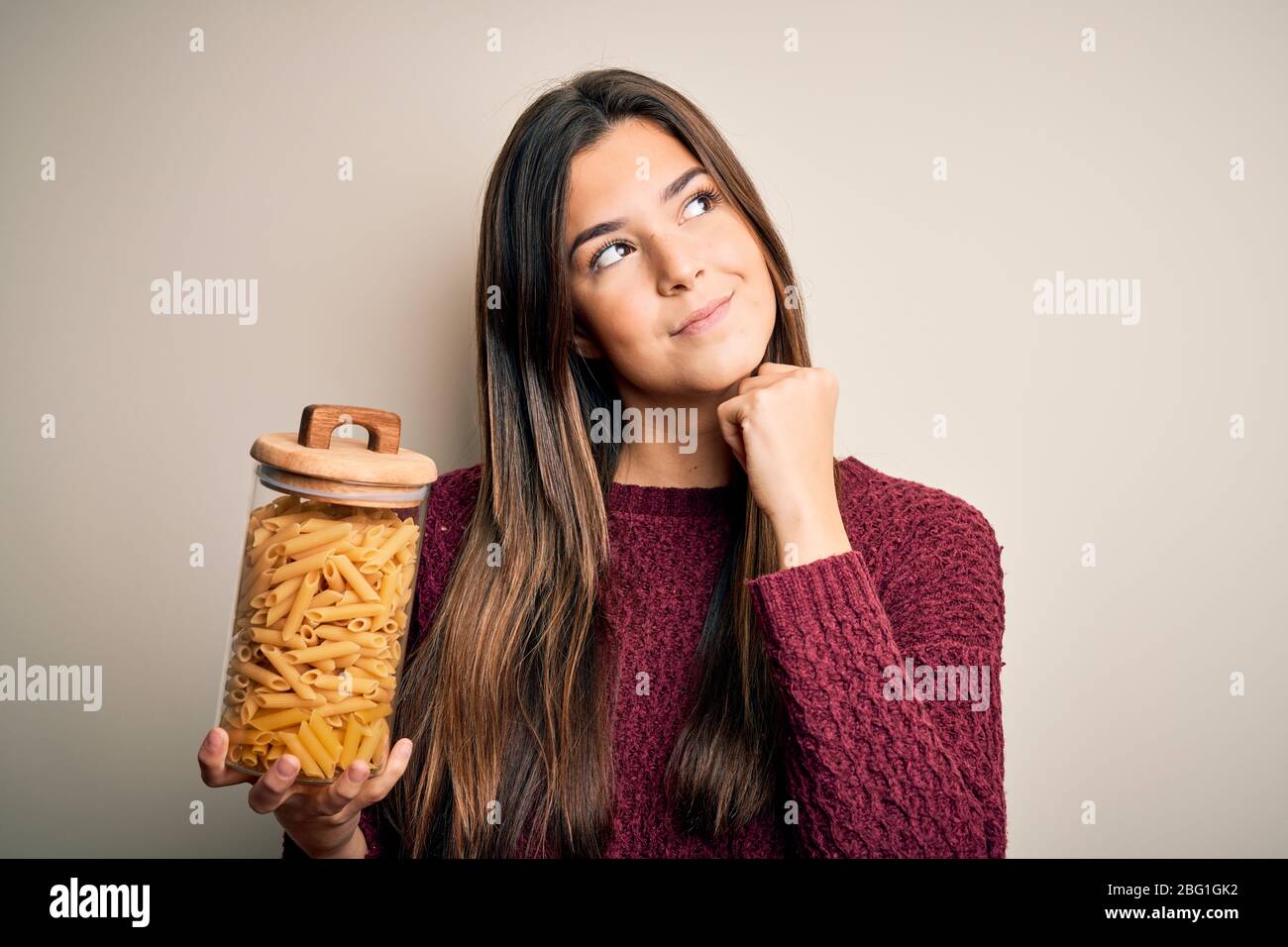 Young beautiful girl holding bottle of dry Italian pasta macaroni over ...