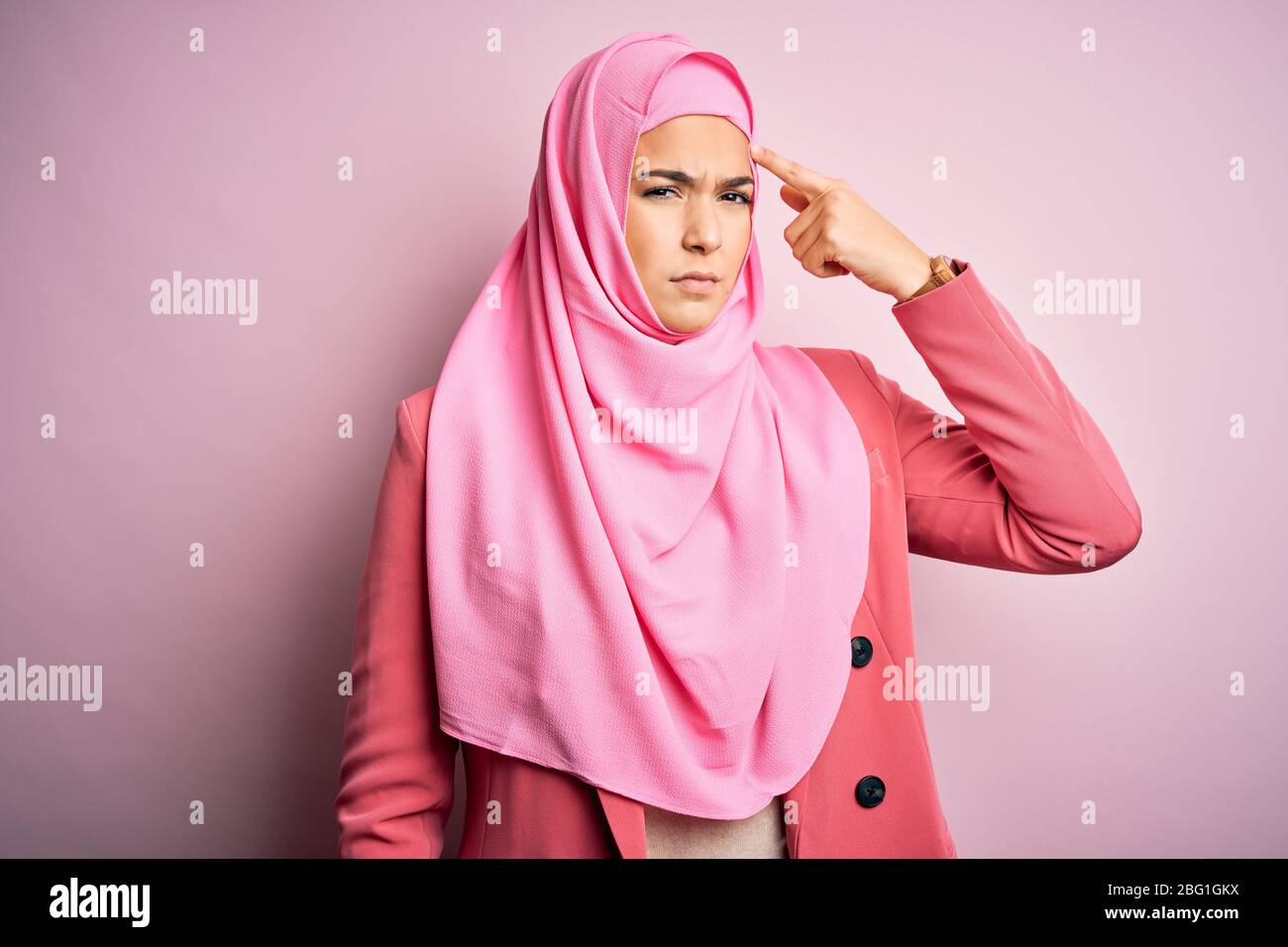 Young beautiful girl wearing muslim hijab standing over isolated pink ...