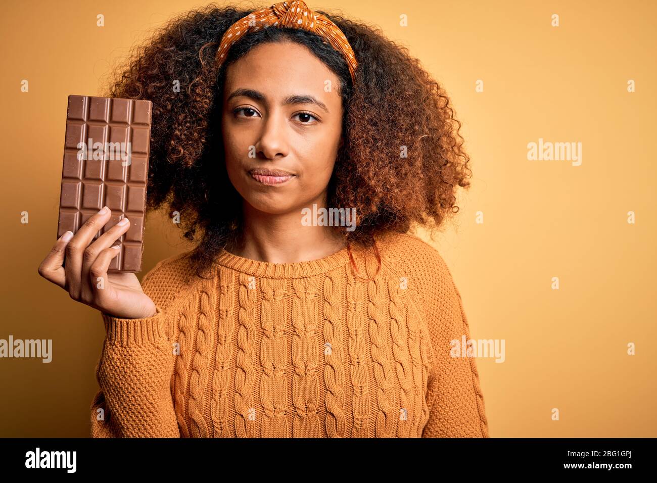 Young african american woman with afro hair holding chocolate bar over ...