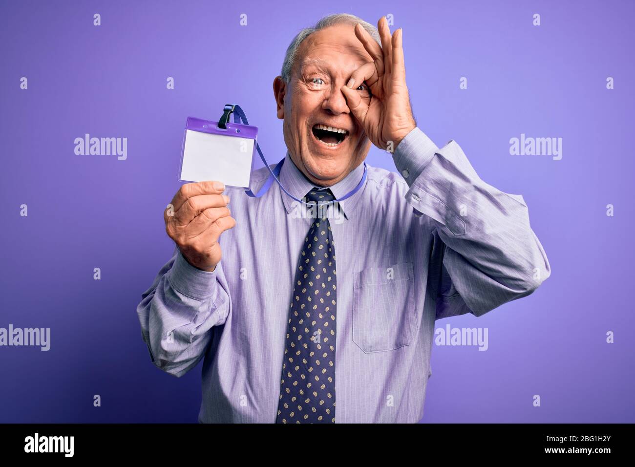 Senior grey haired business man holding identification tag over purple ...
