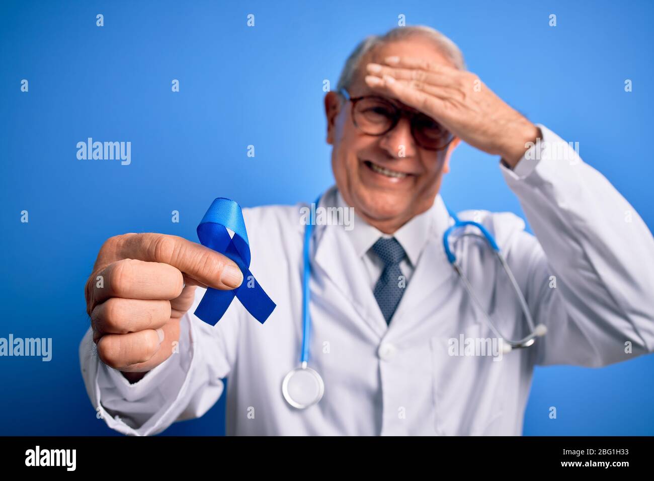 Grey haired senior doctor man holding colon cancer awareness blue ...
